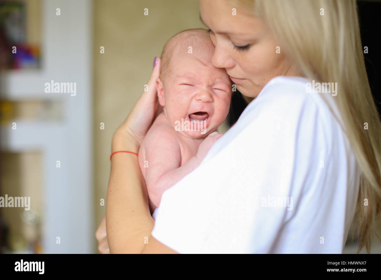 Young mother lulls and sings soothing song, gently hugging, kissing and ...