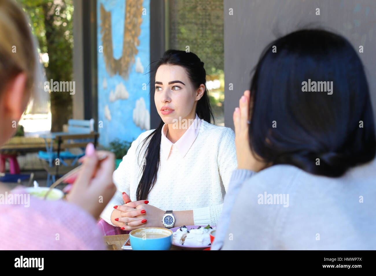 Three girls talking and sit in cafe. Attractive young adult girl with ...