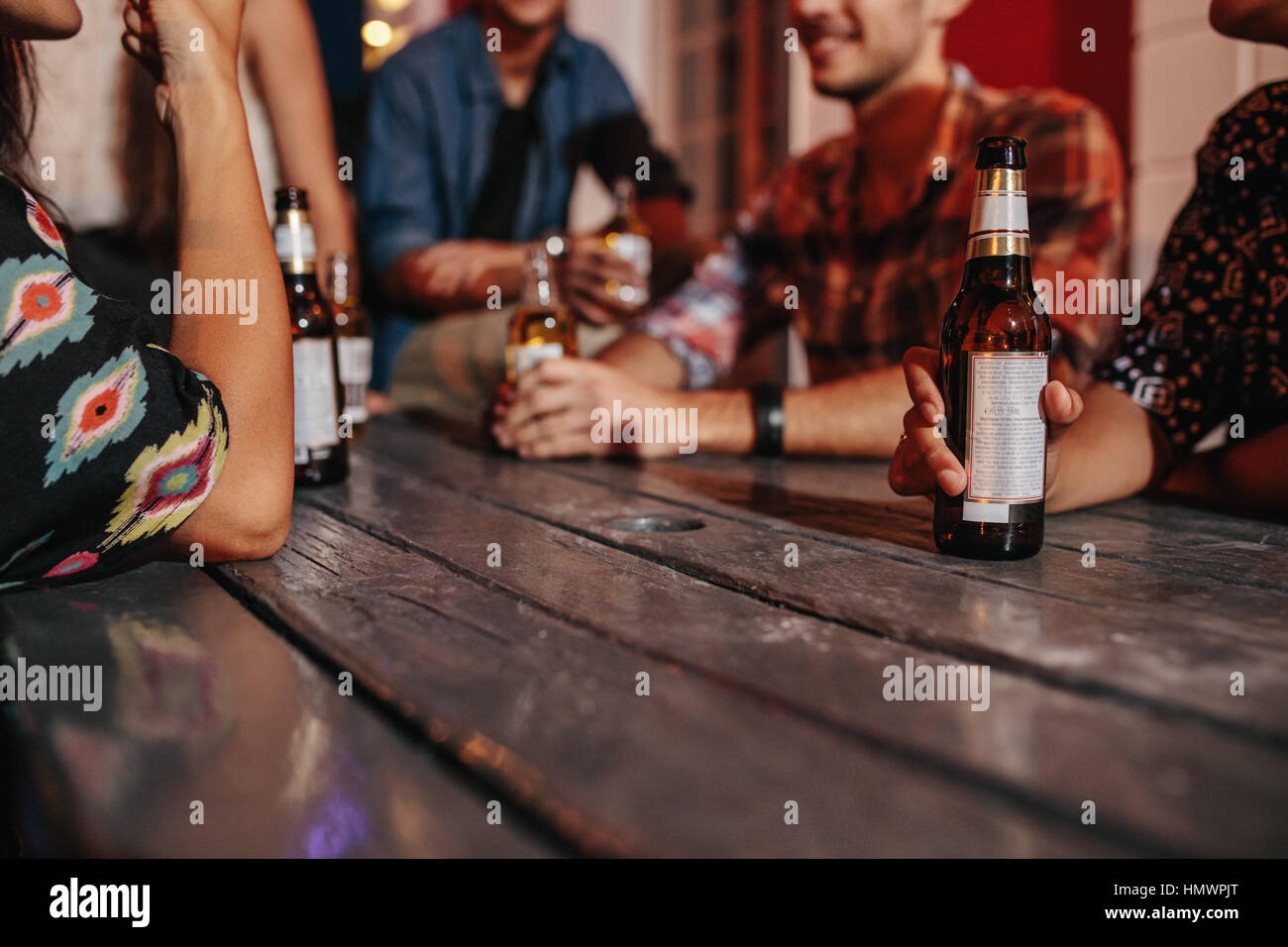 Group of friends sitting around a table having drinks. Focus on beer ...
