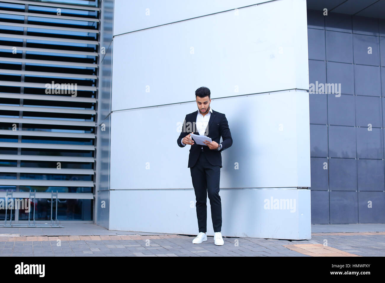 Young tall handsome arab entrepreneur guy student holds and considers ...