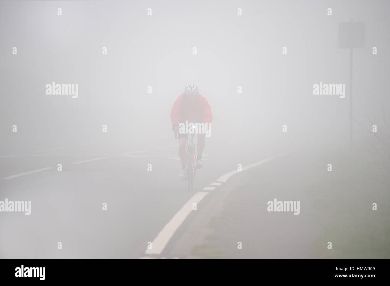 A cyclist cycling in the fog at Denby Dale, Kirklees, West Yorkshire ...