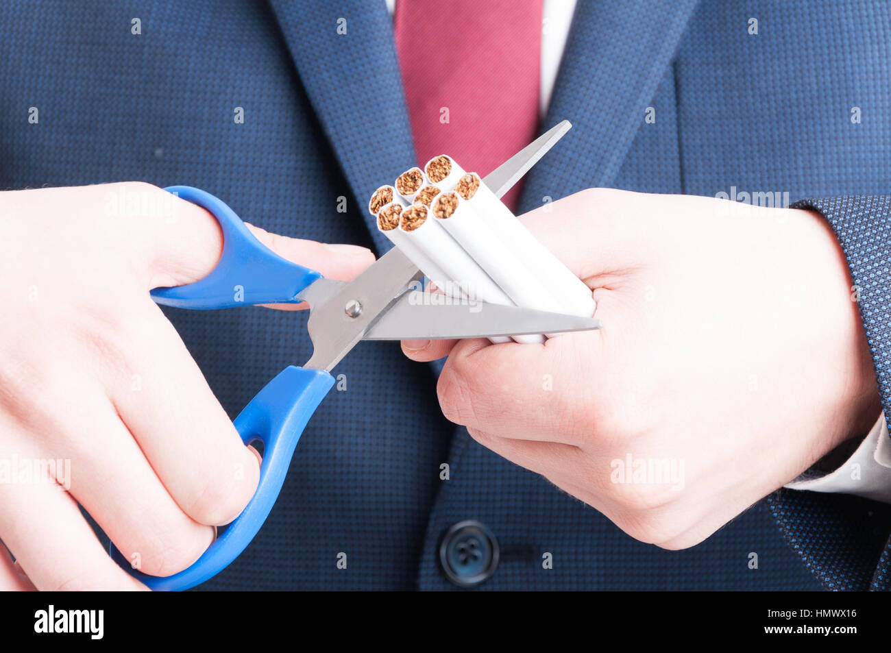 Close-up of man in suit cutting bunch of cigarettes with scissors ...