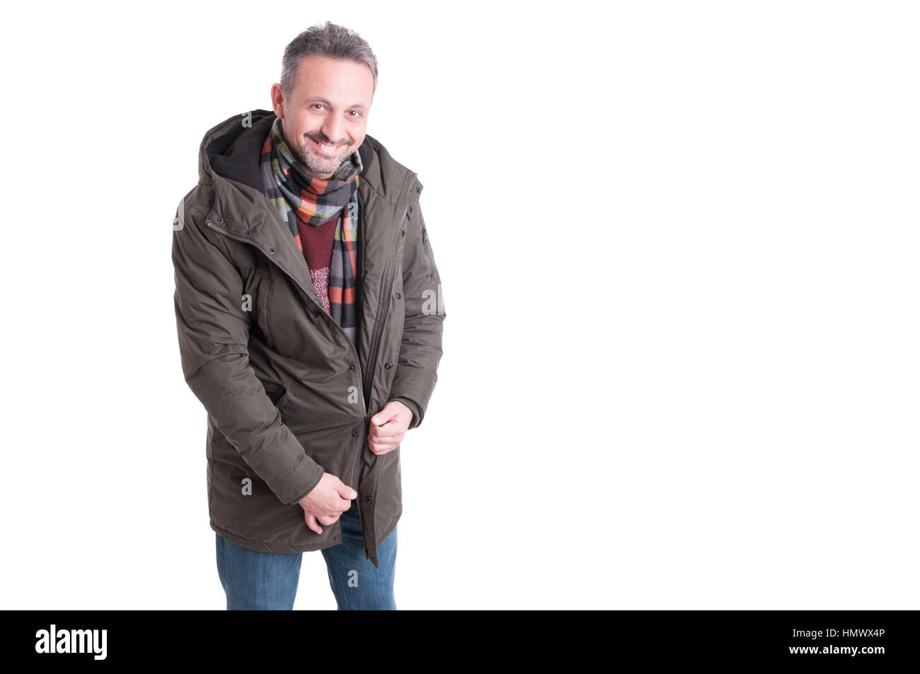 Man smiling and zipping his winter jacket isolated on white background ...