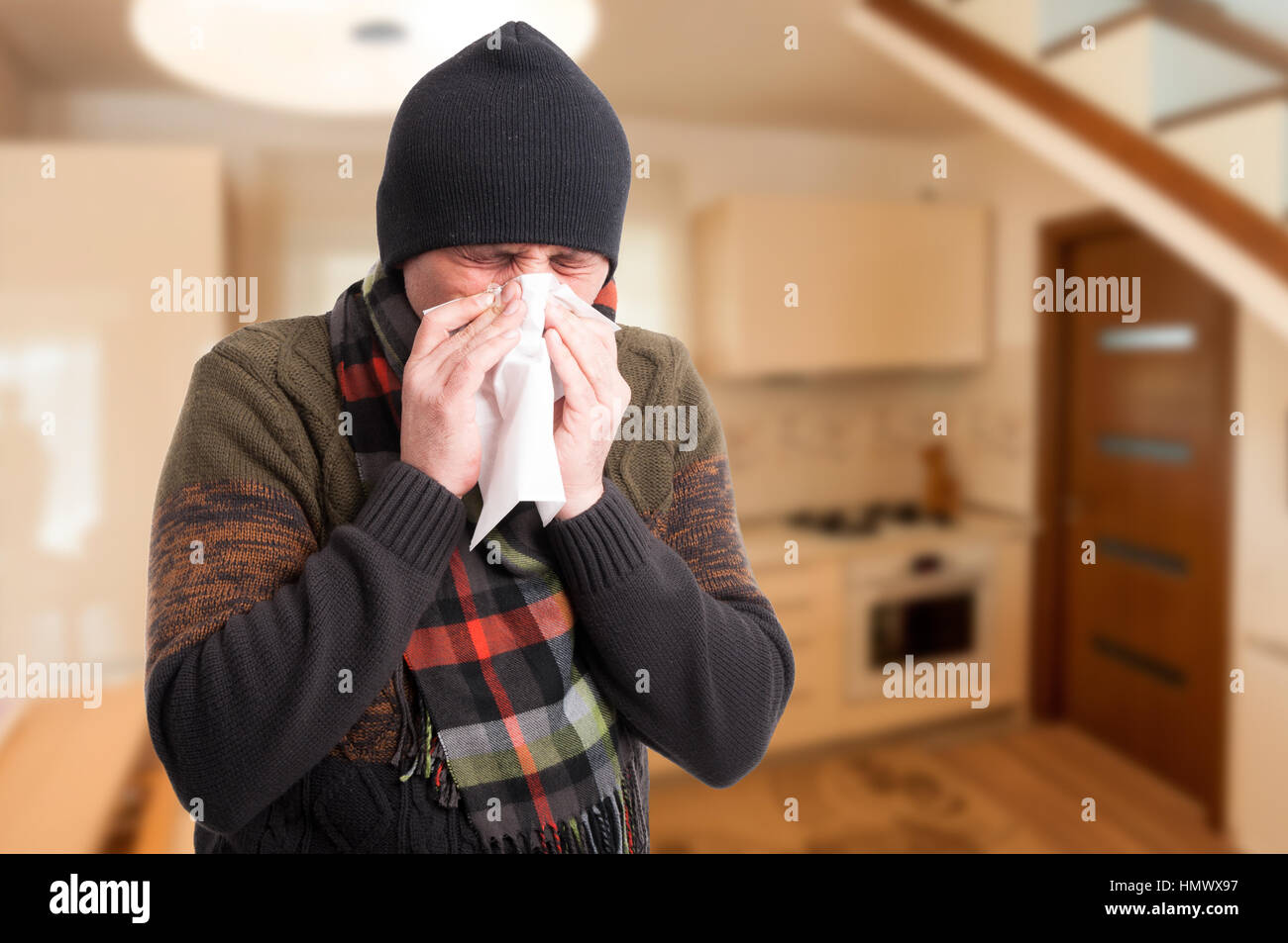 Young sick man holding tissue and blowing nose inside the house with ...