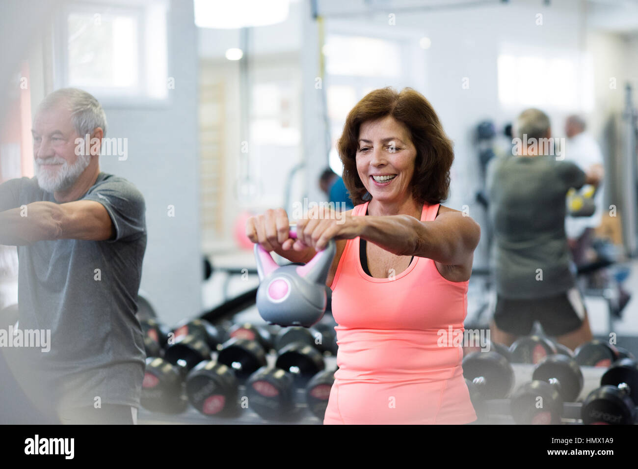 Senior couple in gym working out using kettlebells Stock Photo - Alamy
