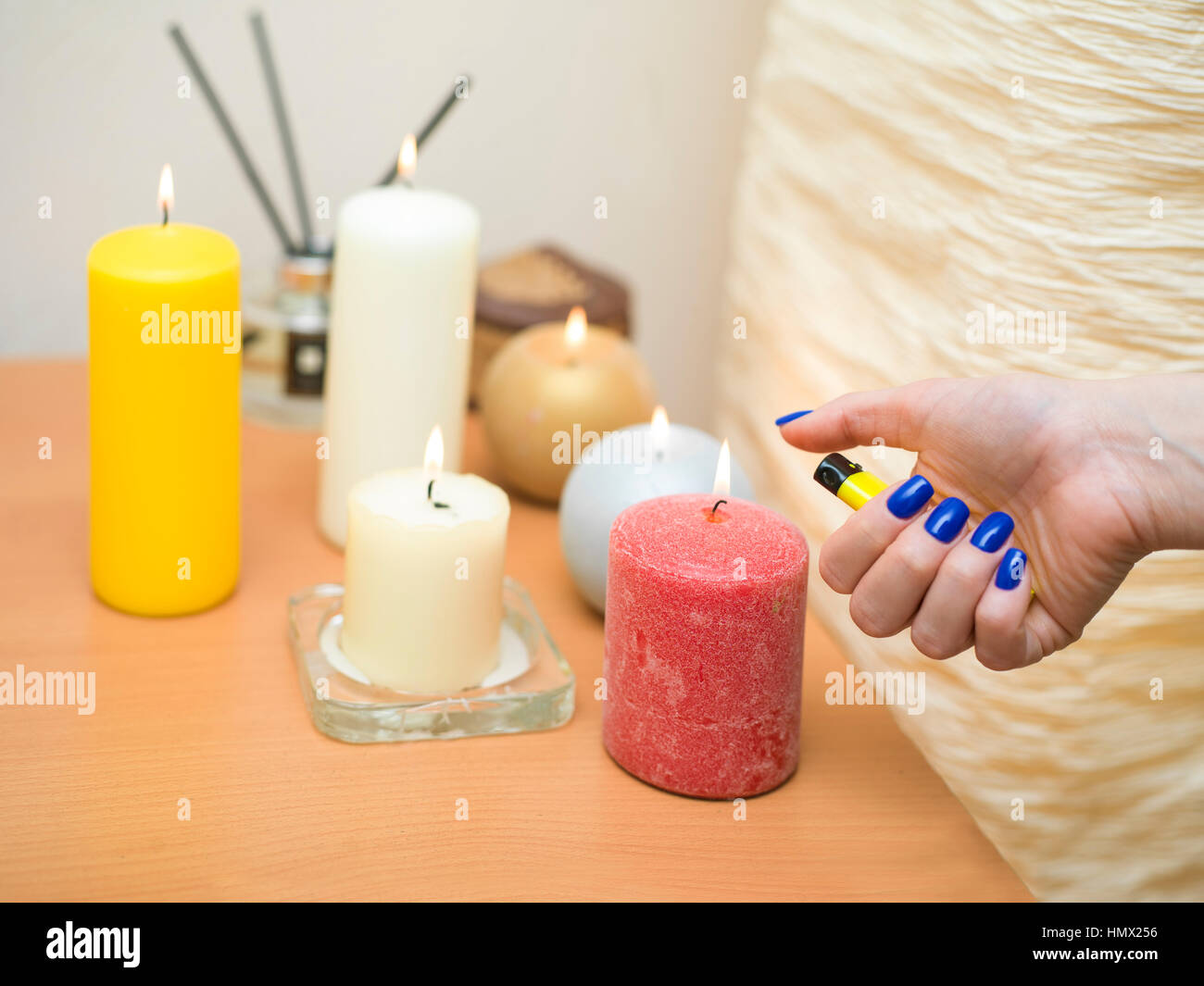 Female hand with a lighter next to the aromatic candles, closeup indoor ...