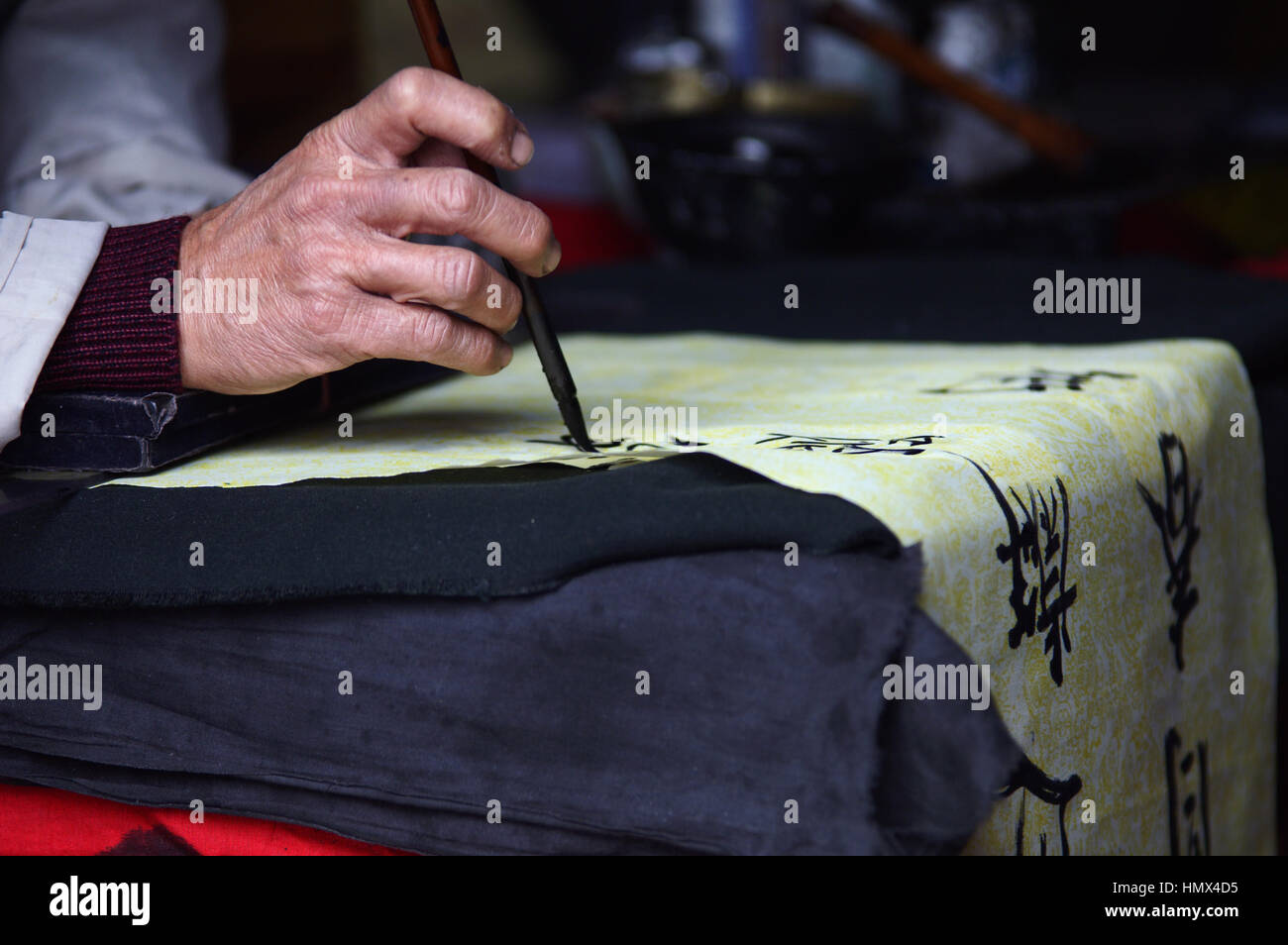 Close up of old man's hand writing ancient chinese characters on a ...