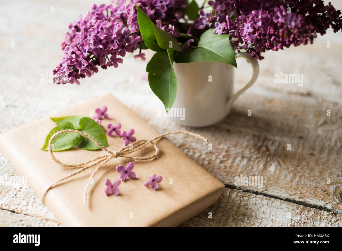 Purple lilac bouquet in vase and present laid on wooden table Stock ...