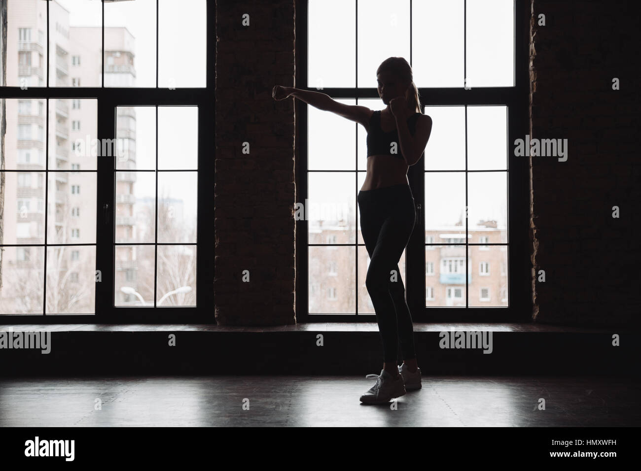 Silhouette of woman athlete standing and doing shadow boxing exercises ...