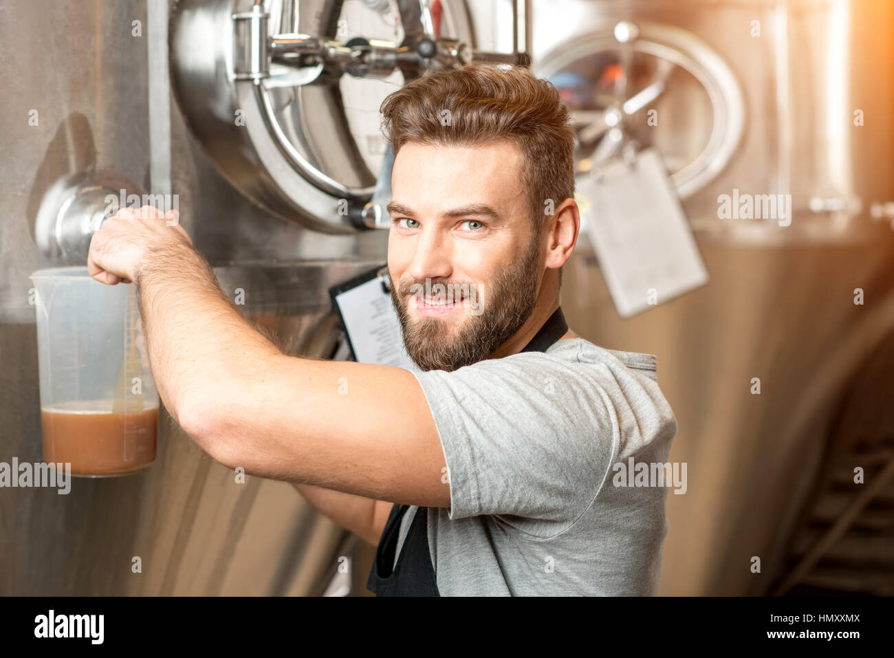 Brewer pouring beer wort from the metal container checking the quality ...