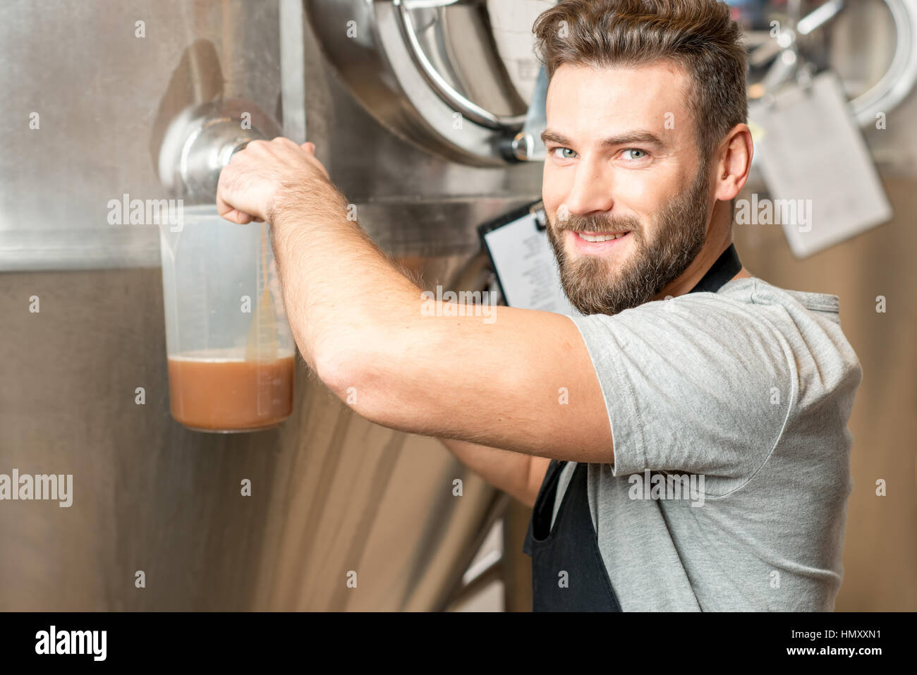 Brewer pouring beer wort from the metal container checking the quality ...