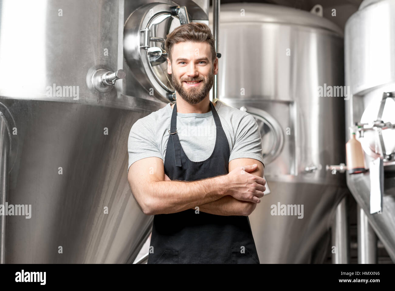 A portrait of handsome brewer in uniform at the beer manufacture with ...