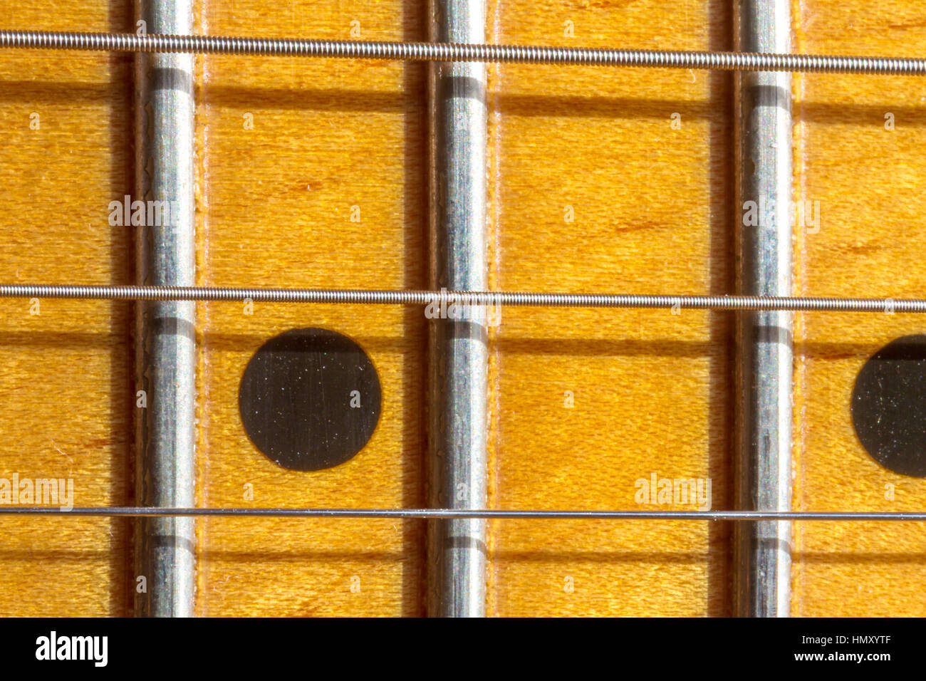 Close up of an electric guitar maple fret board and strings showing the ...