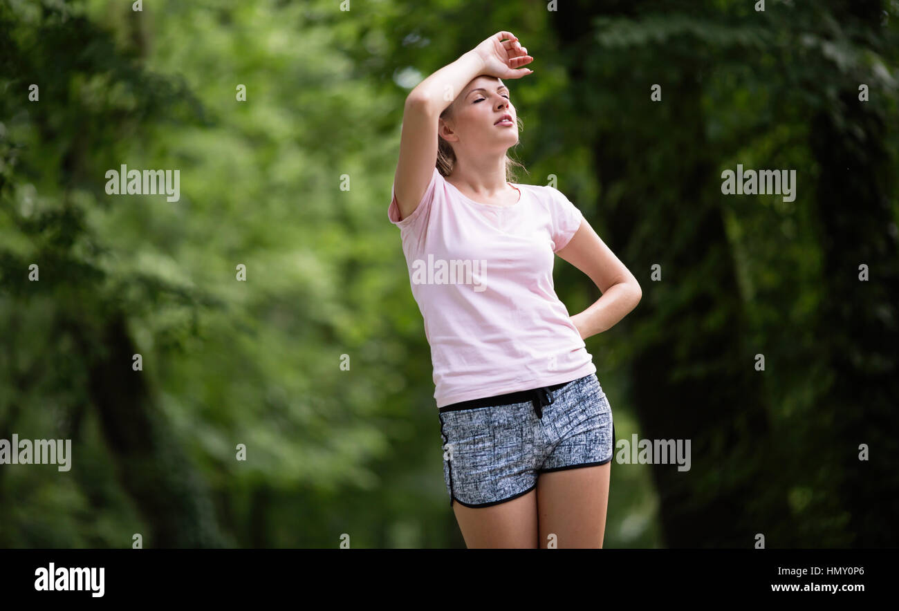 Exhausted female jogger grasping for air in park Stock Photo - Alamy