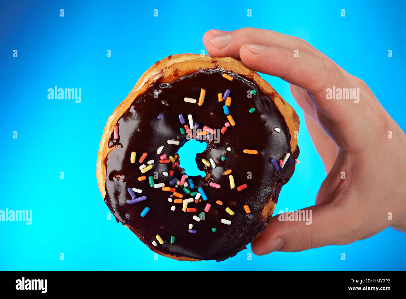 close up of hand hold one donut isolated on blue Stock Photo - Alamy