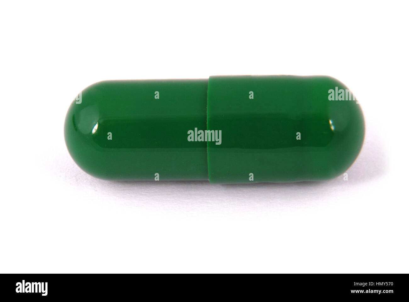 One capsule pill with green color on white background with soft shadow ...