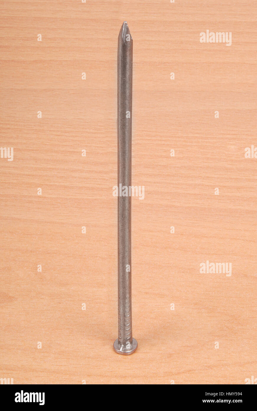 Large metal nail standing on a wooden board Stock Photo - Alamy