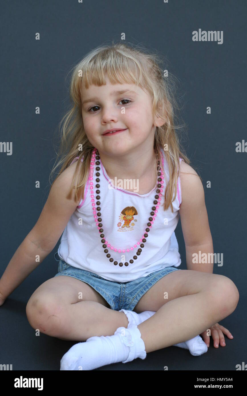 Little girl with blonde hair and a fringe smiling wearing beads Stock ...