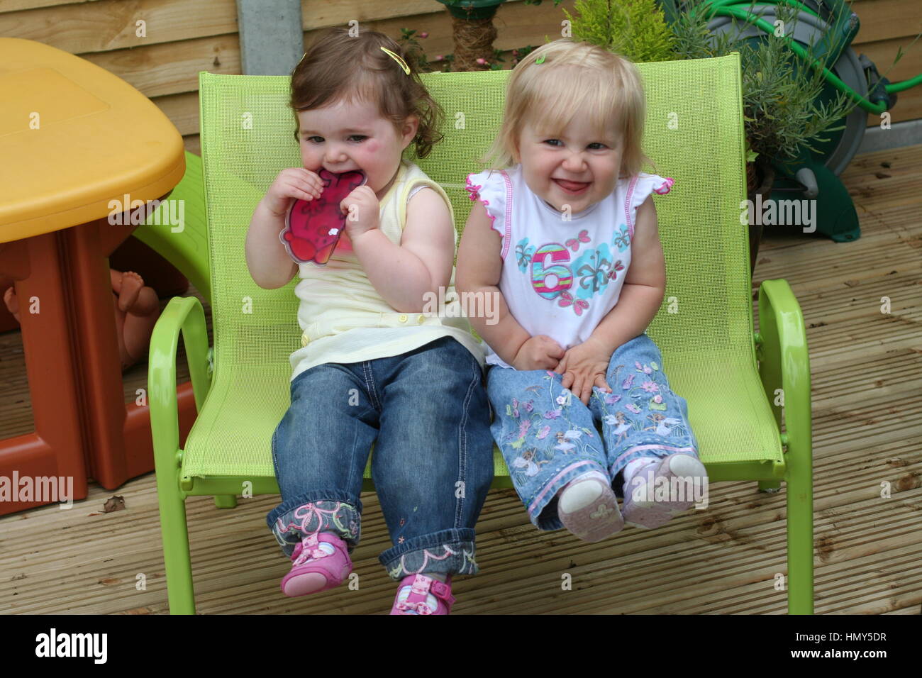 Toddlers, two little girls sitting together in the garden playing ...
