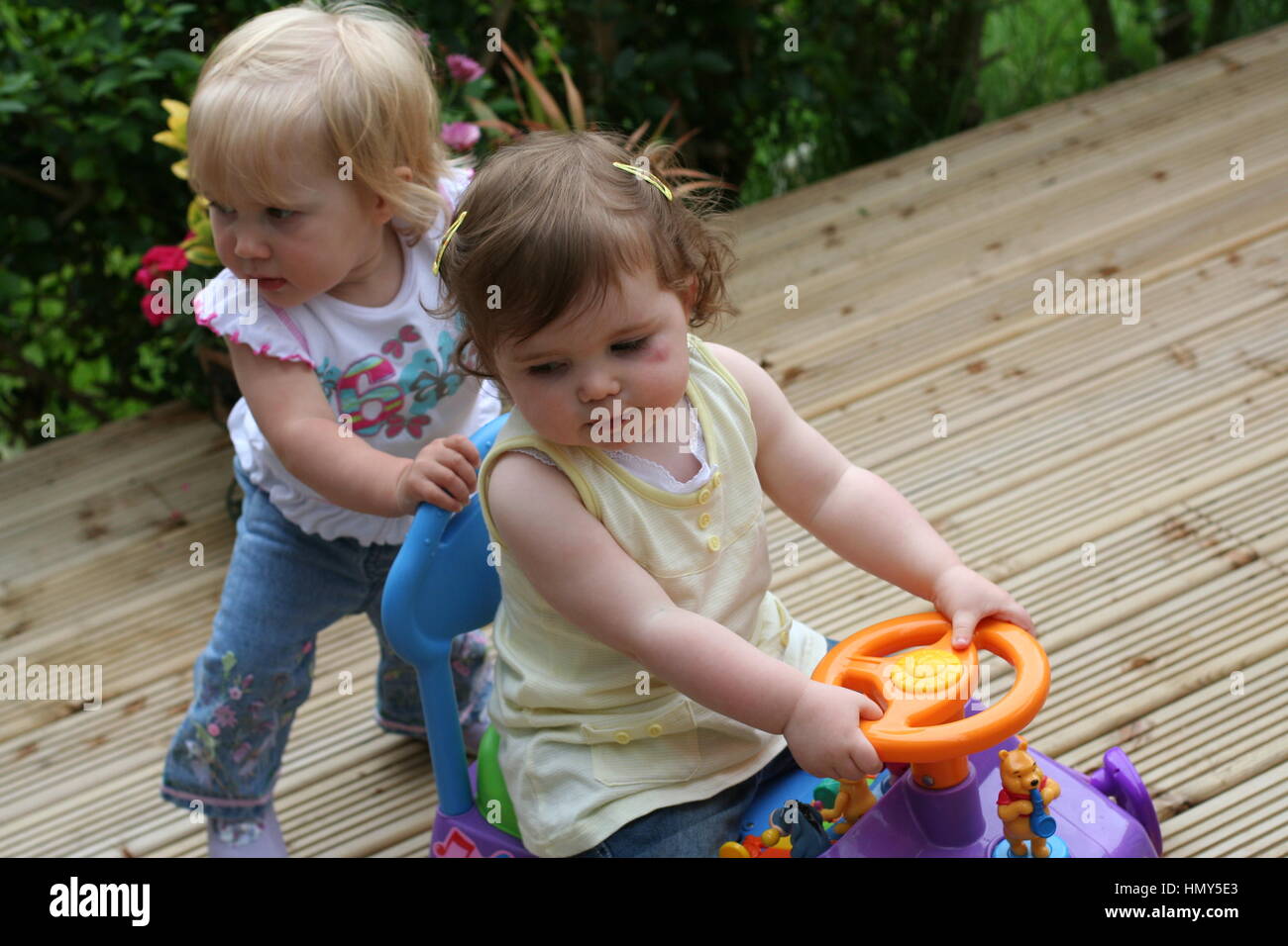 Toddlers, two little girls playing together in the sunshine sitting on ...