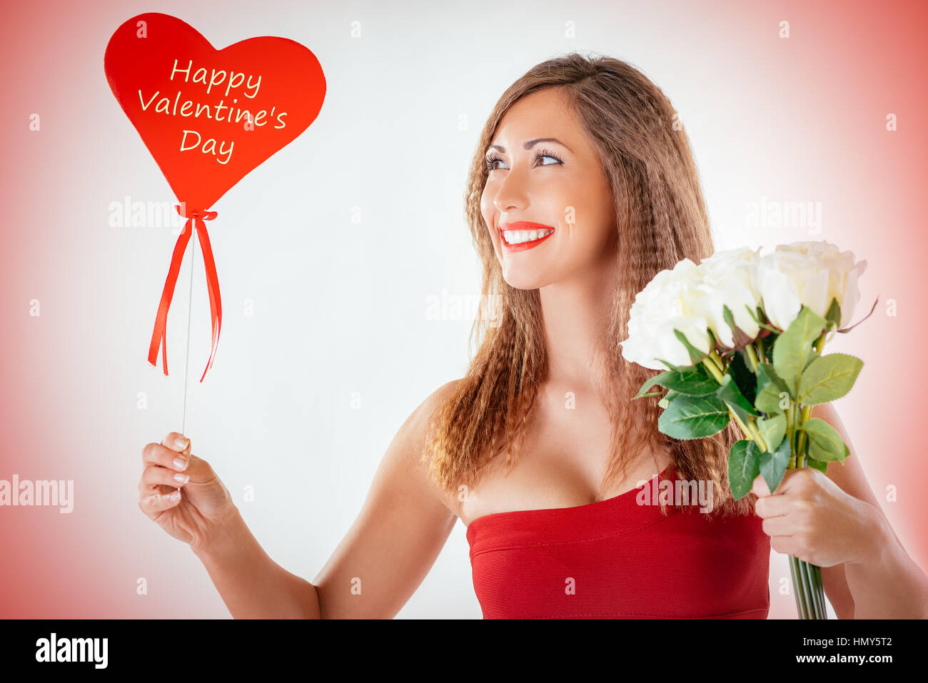 Portrait of a beautiful smiling girl holding a red heart and bouquet ...