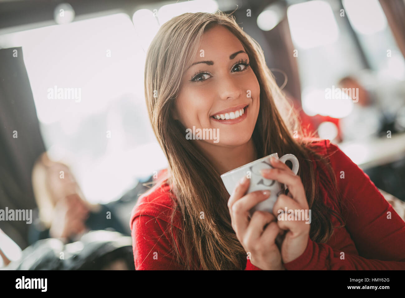 Beautiful young smiling woman relaxing and enjoying a cup of coffee at ...