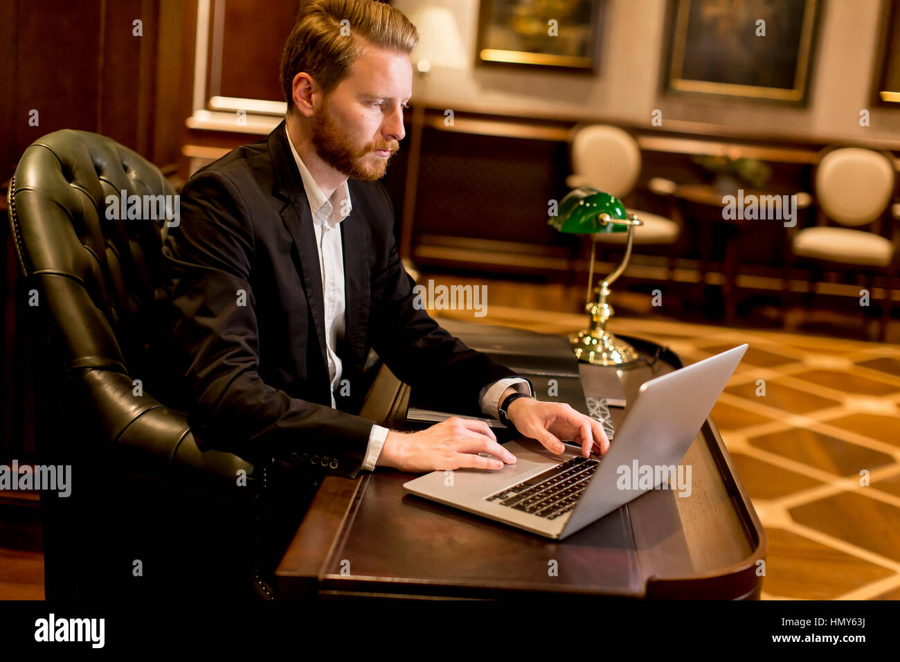 Young business man sitting at a desk and working on his laptop in ...