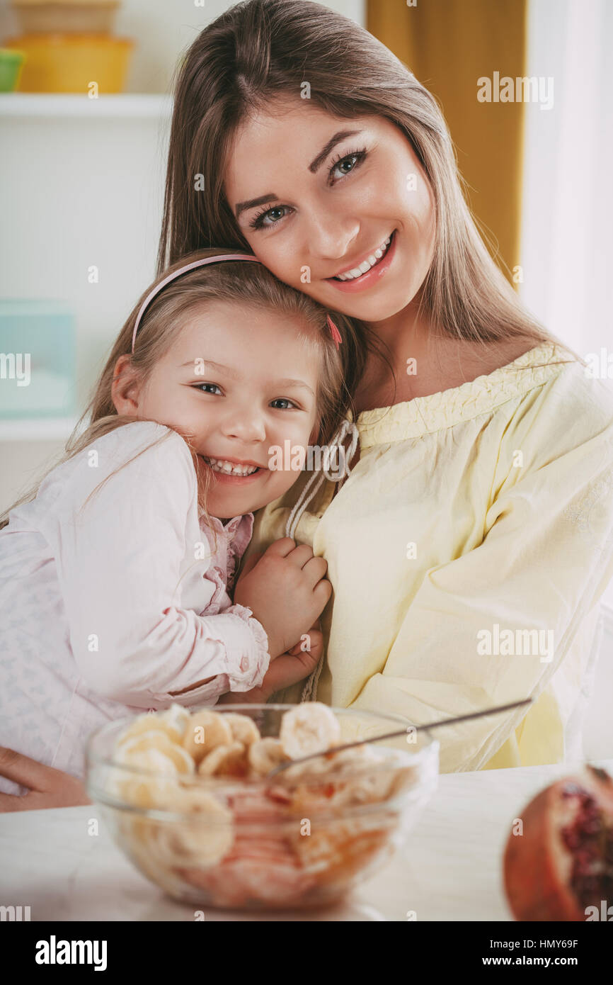 Mother and daughter having breakfast in the kitchen. They eating fruit ...