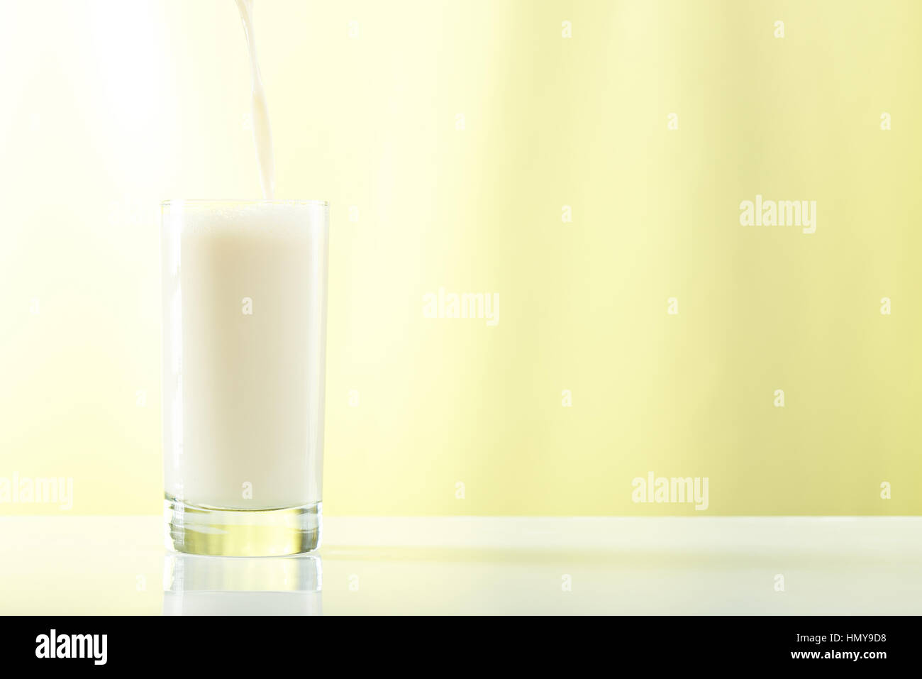 pouring milk in tall glass isolated on yellow background Stock Photo ...