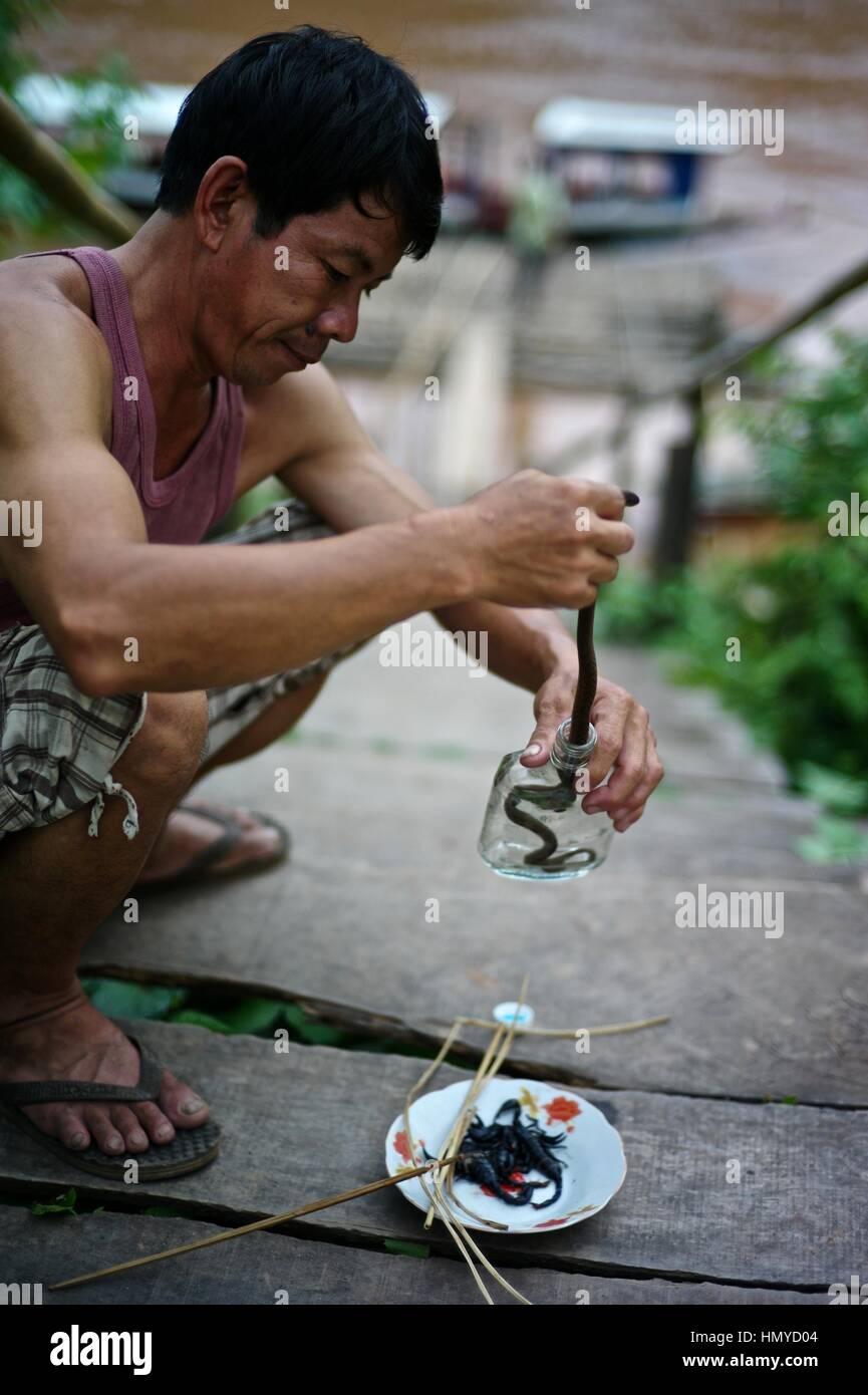 A man prepares Lao Lao whiskey in Whisky Village, known as Ban Xang Hai ...