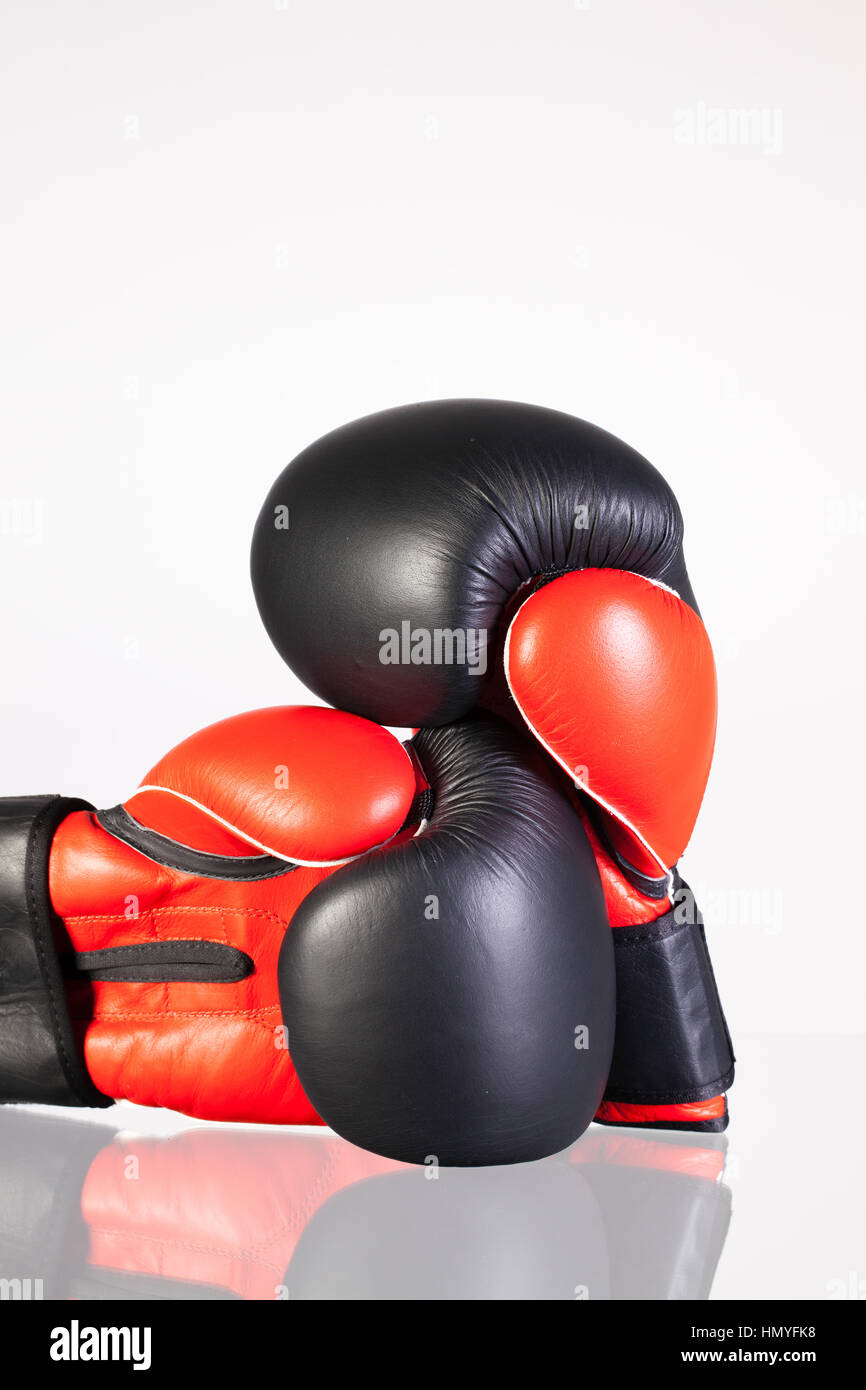 Red and black boxing gloves on a glass table isolated on white ...
