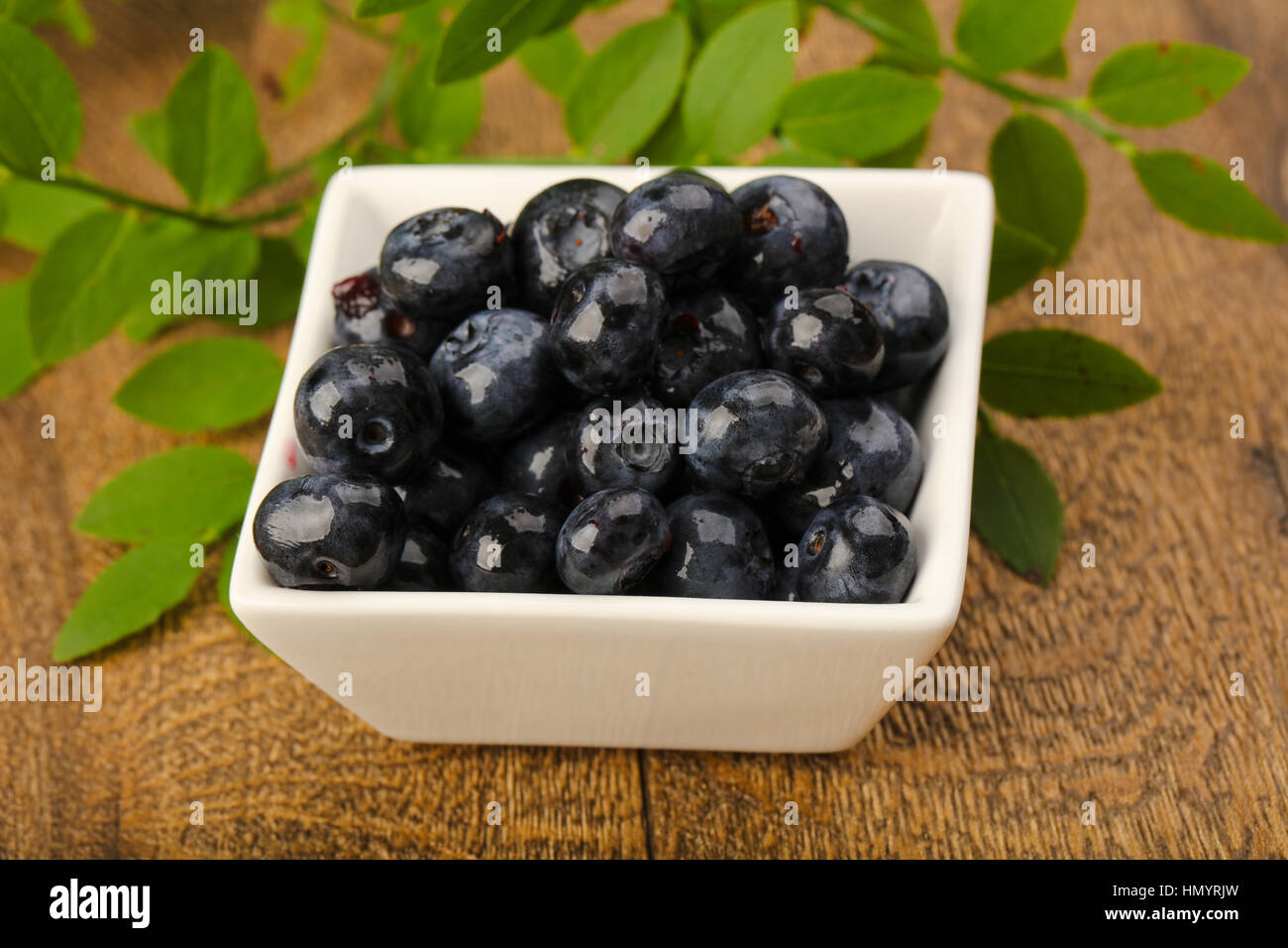Ripe Blueberry heap with leaves on wood background Stock Photo - Alamy
