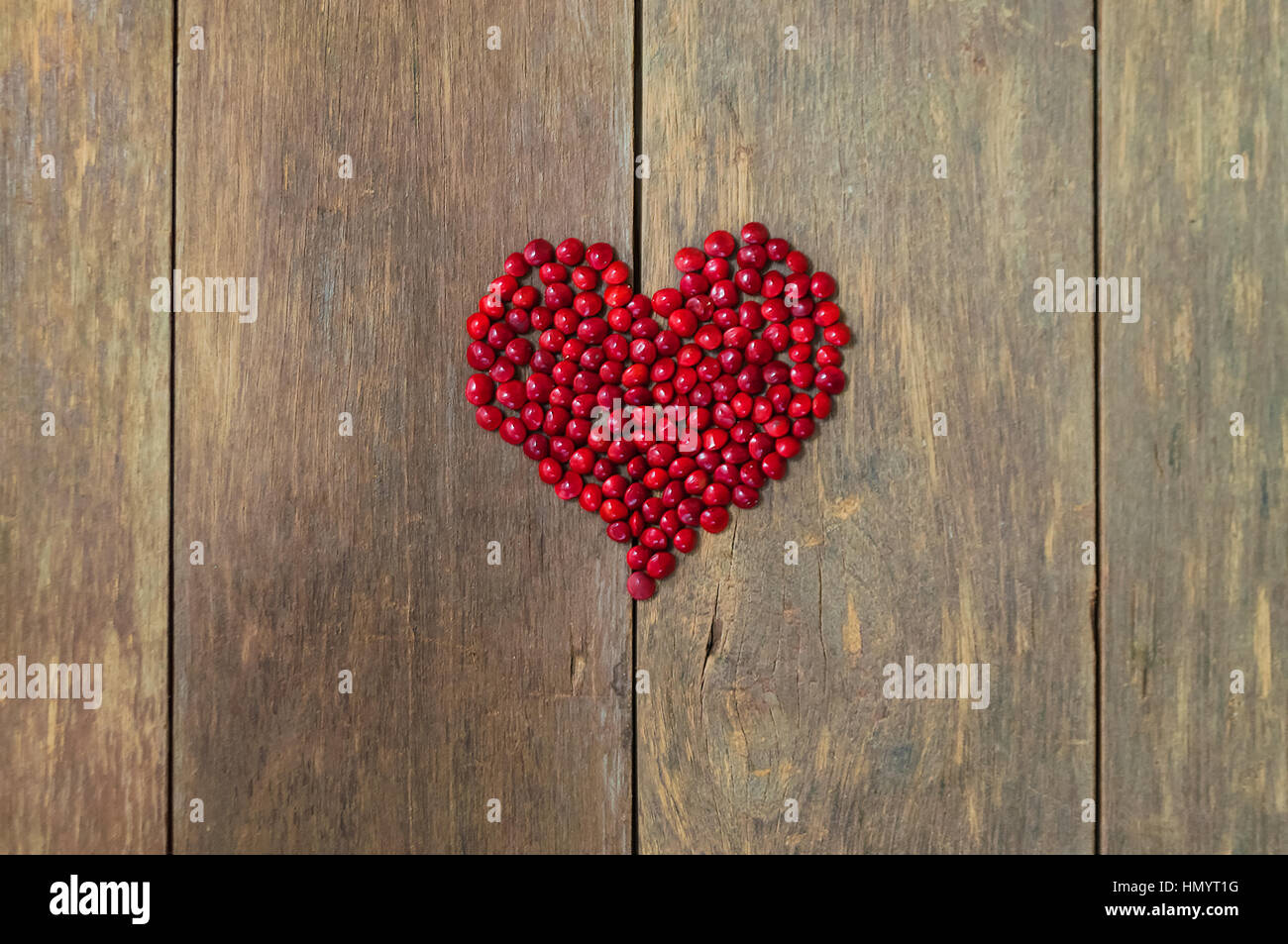 Red bead tree seeds arranged in heart shape on brown wood planks Stock ...