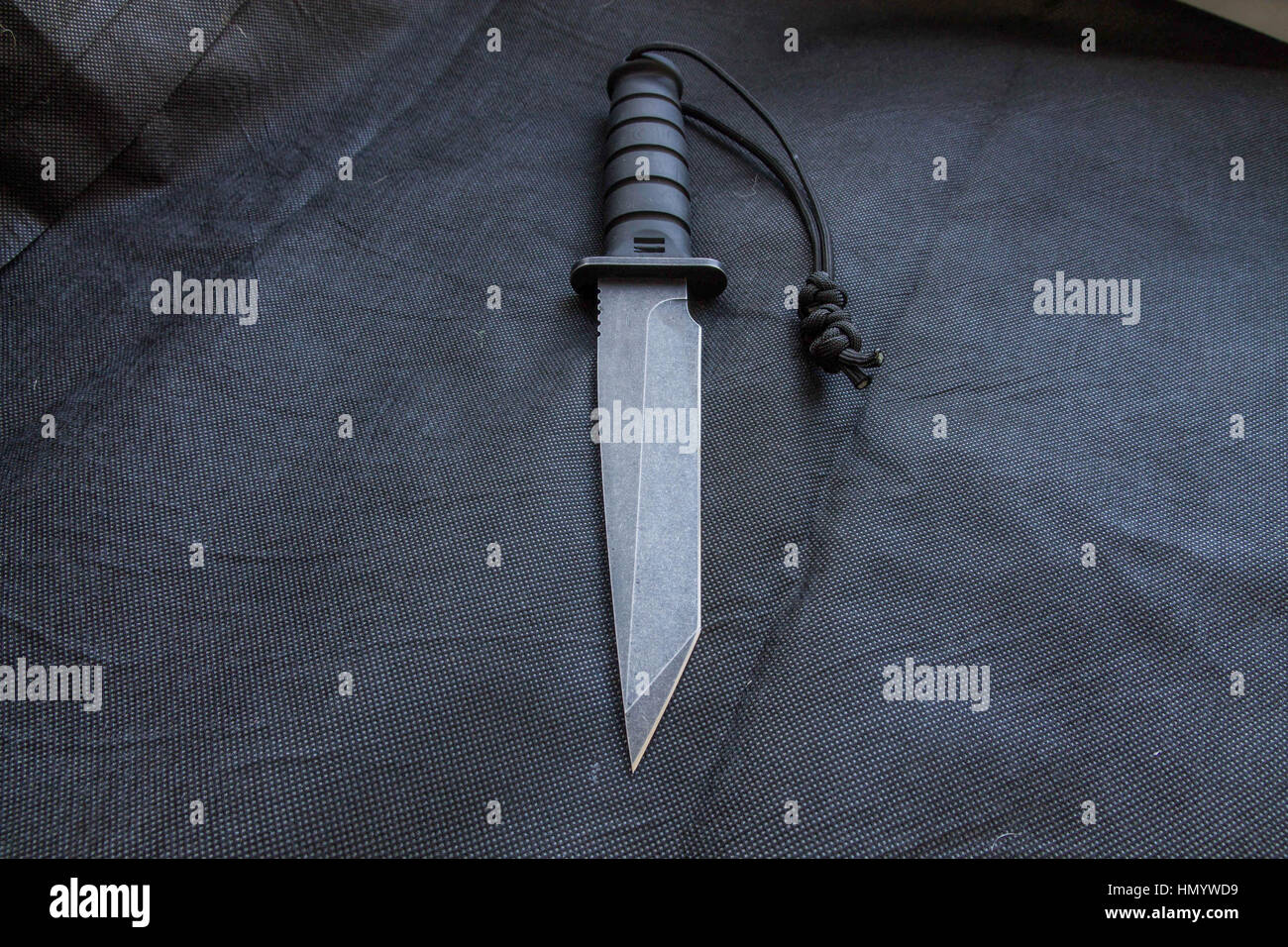 Military knife in the center of the frame. Black knife on a black ...