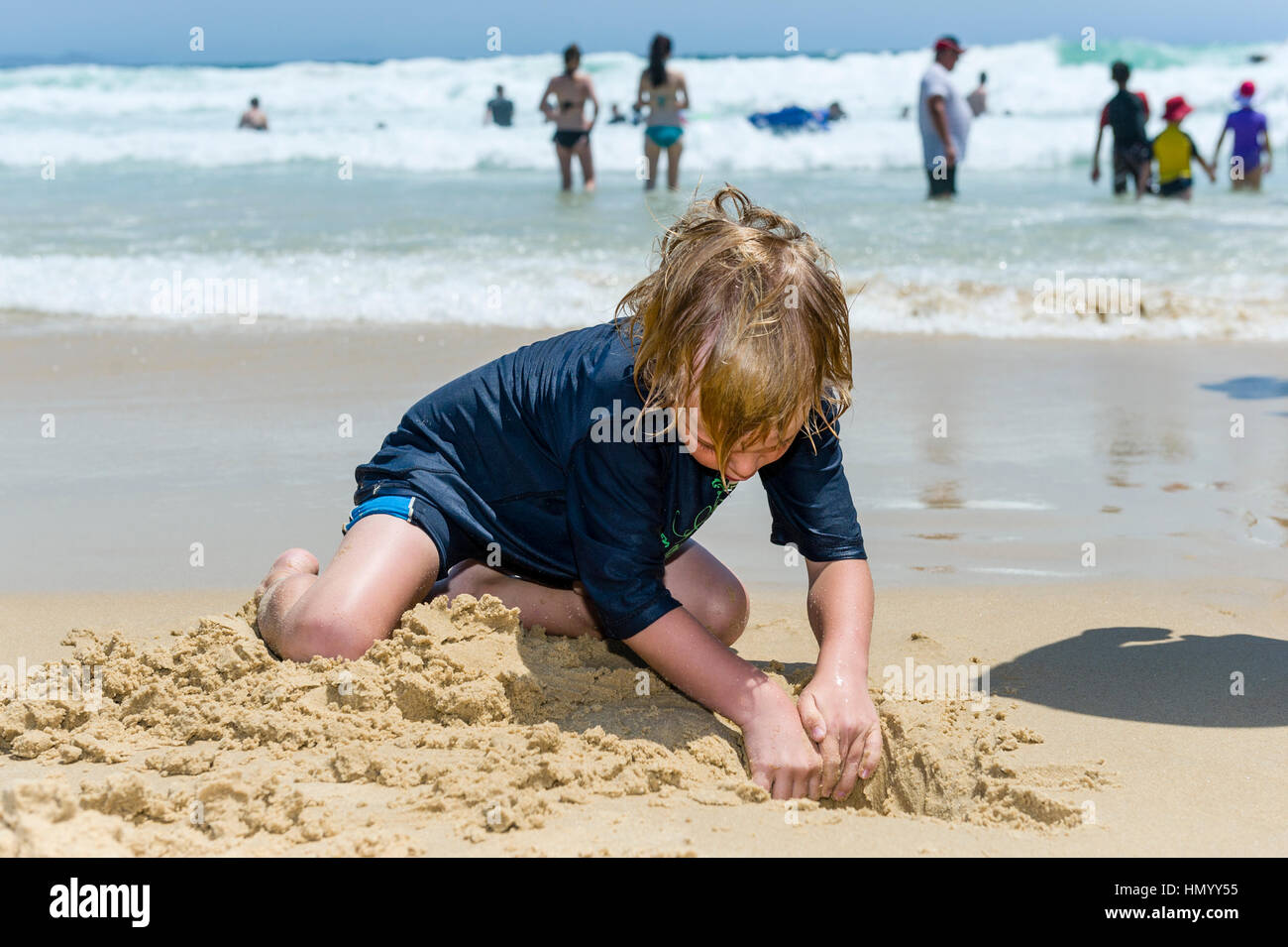 A boy digging in the sand on a beach at low tide Stock Photo - Alamy