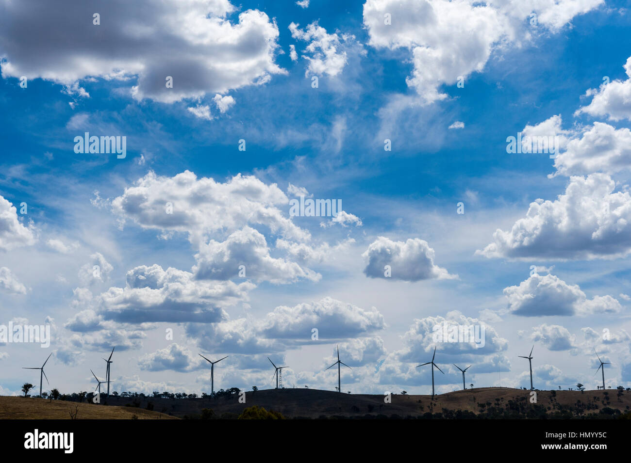 Fluffy white clouds above the blades of a wind turbine farm on a ...