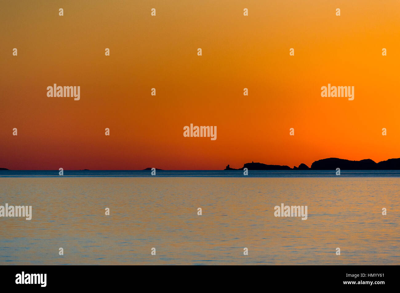 Flaming red afterglow over the ocean horizon and coastline at sunset ...