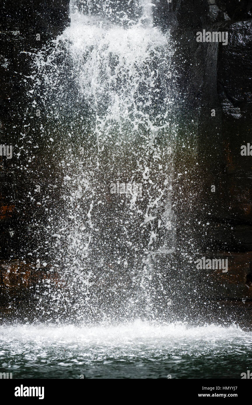 A waterfall cascades down a sheer sandstone cliff covered in ...