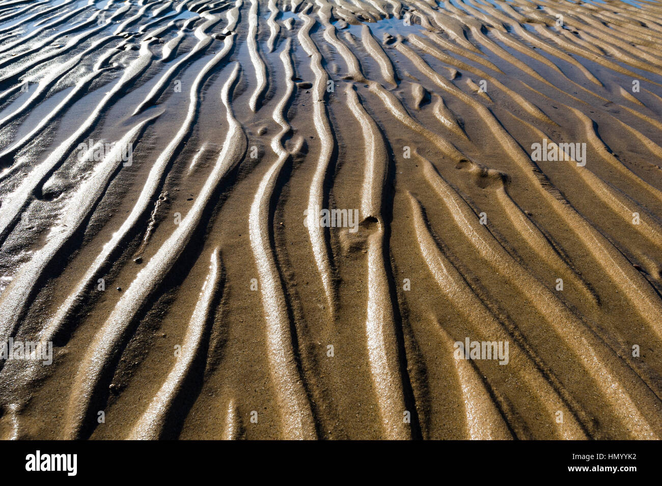 Sand patterns wave and snake their way across a beach at low tide Stock ...