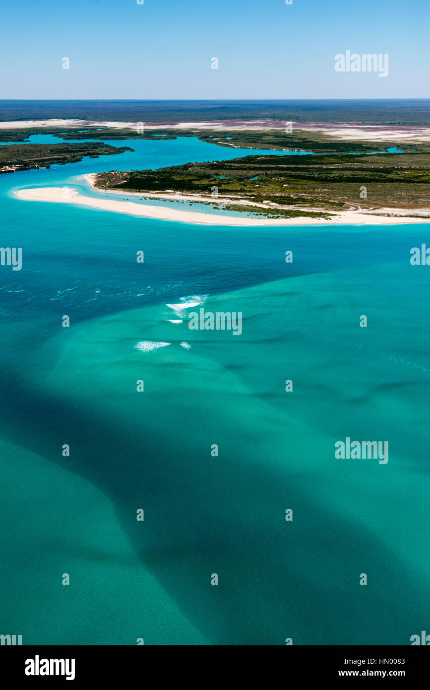 A tidal river inlet and white sandy beach in a pristine turquoise sea ...