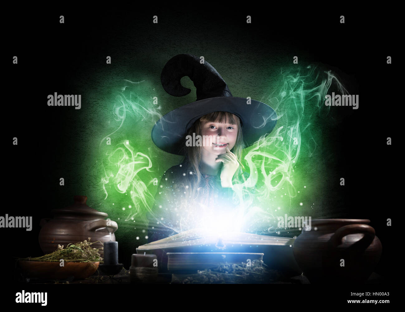 Little Halloween witch reading conjure from magic book above pot Stock ...