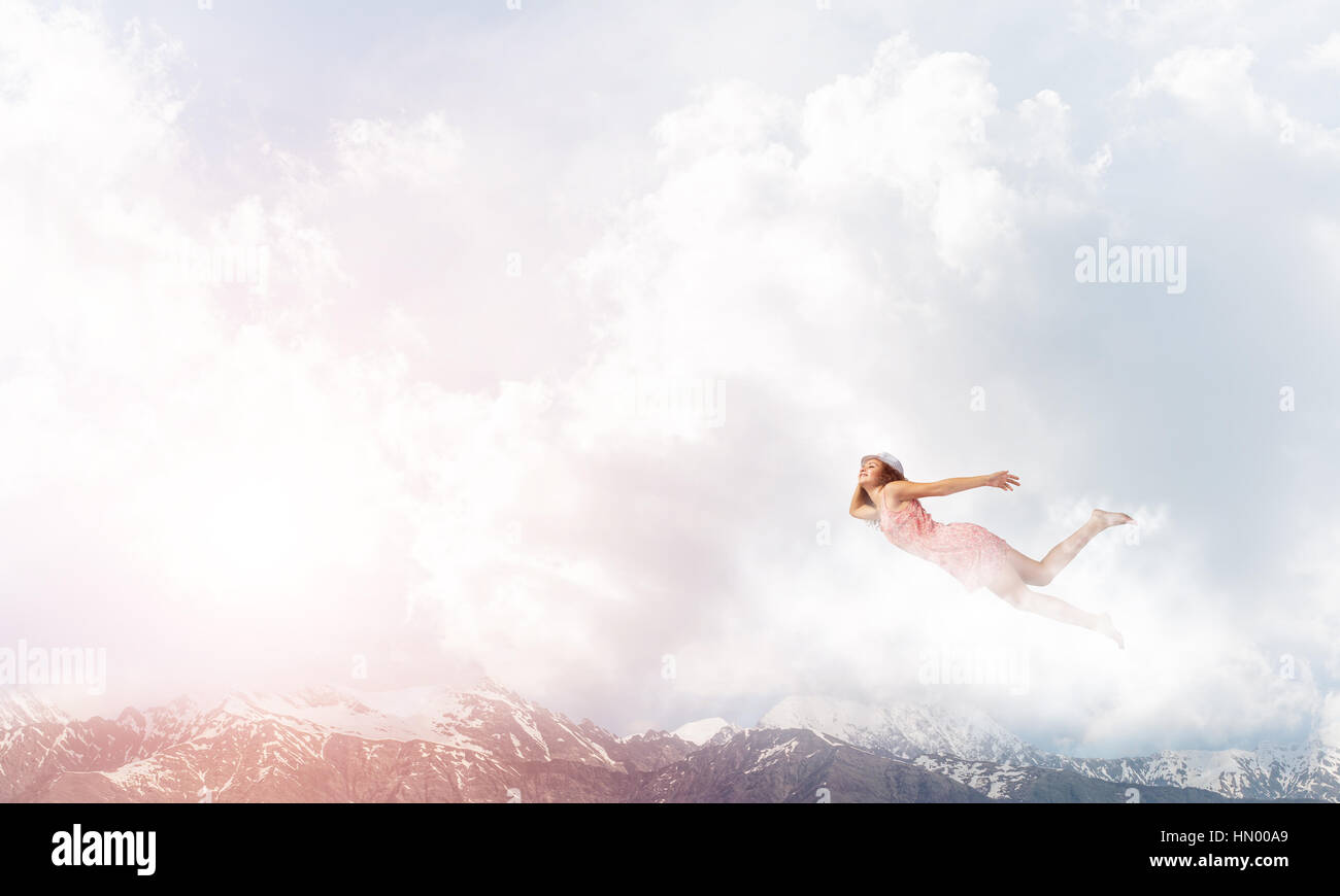 Young woman flying high in blue sky Stock Photo - Alamy
