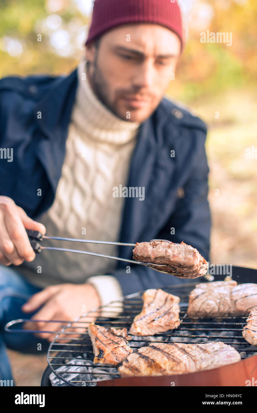 Man cooking meat on charcoal grill Stock Photo - Alamy