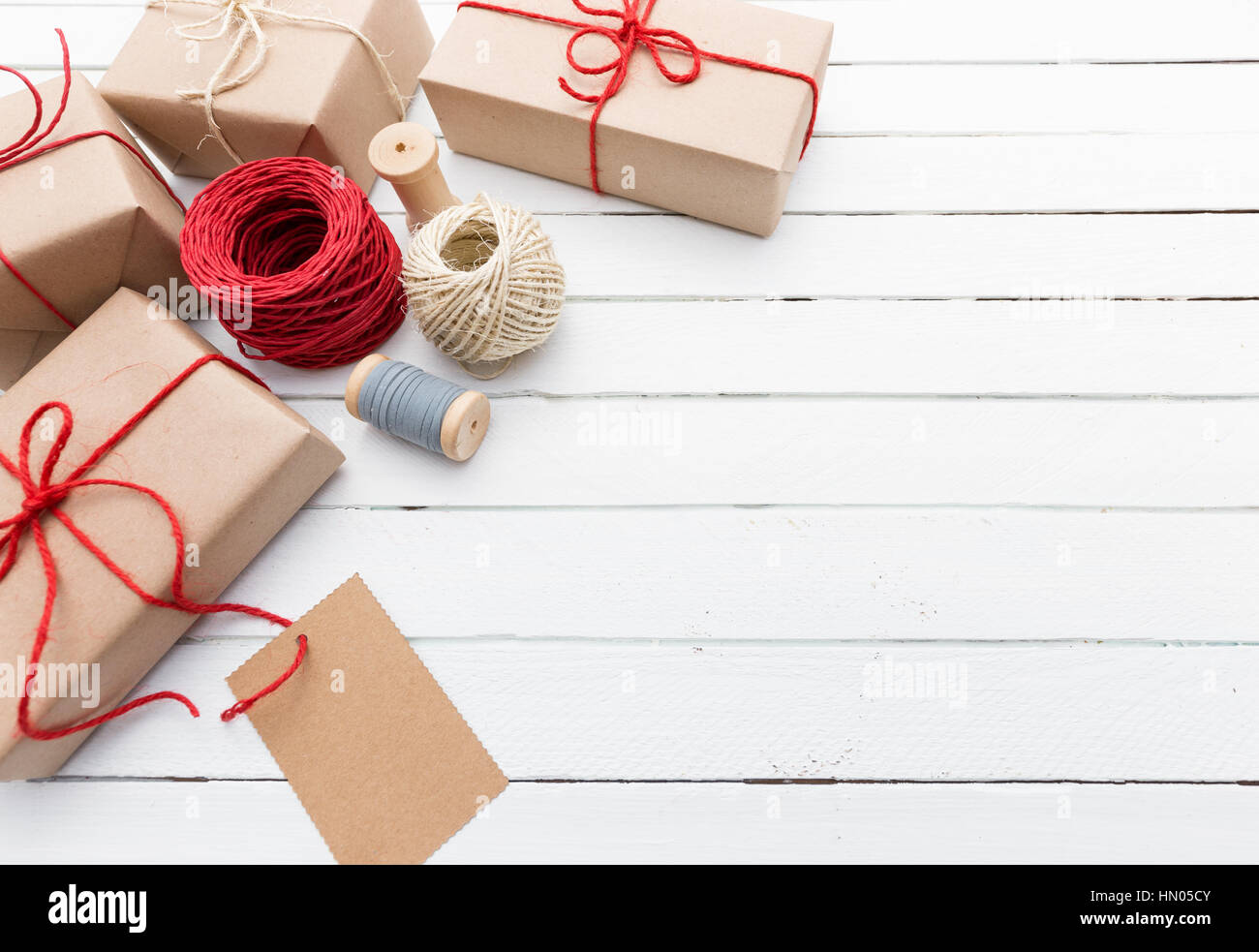 Homemade wrapped rustic brown paper packages on white wooden surface ...
