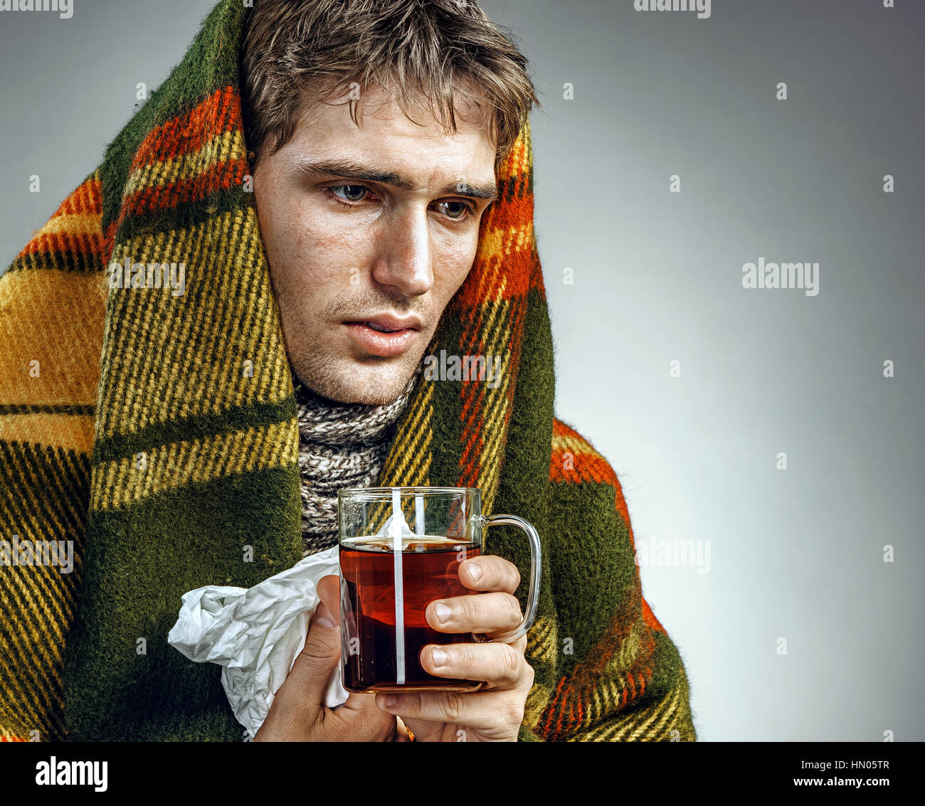 Ill Man covered with plaid blanket with hot tea. Sick man suffering ...
