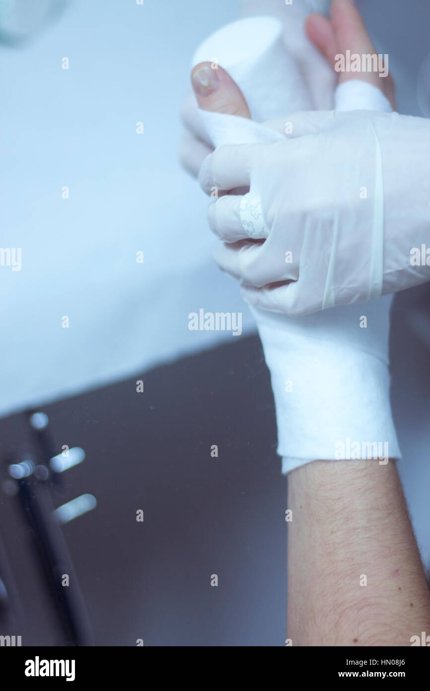 Doctor applying a plaster cast and bandages to patient forearm and ...