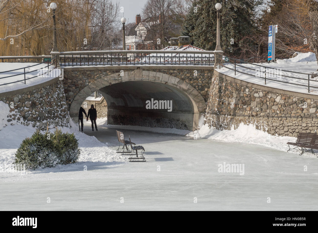 Silhouette of a couple ice skating under an old stone bridge by the ...