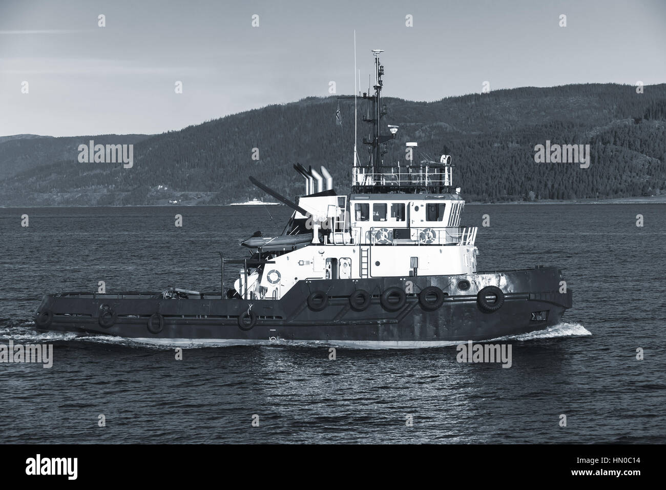 Tug boat with white superstructure underway, side view. Trondheim ...
