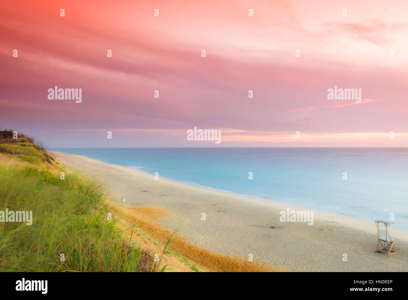 A pastel pink sunrise over the blue Atlantic Ocean at a beach on Cape ...