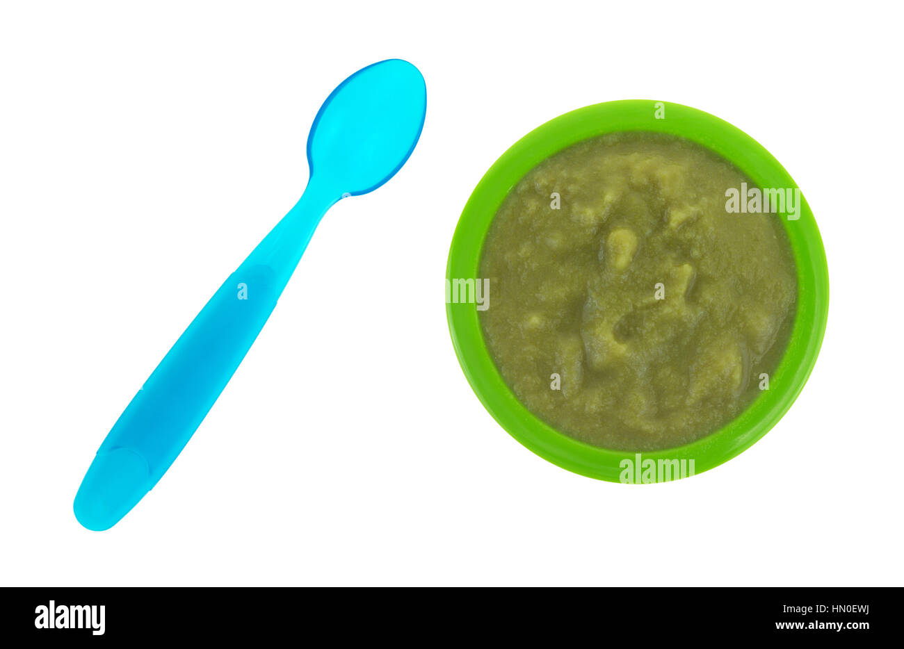 Top view of green peas baby food mush in a small bowl with a blue spoon ...